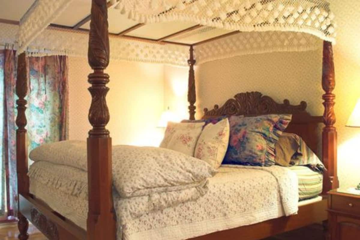 Uma cama de dossel com um cobreleiro estampado com padrão floral e várias almofadas.