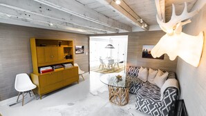 Uma sala de estar moderna com sofá, mesa de centro de vidro, estante e cabeça de veado montada.