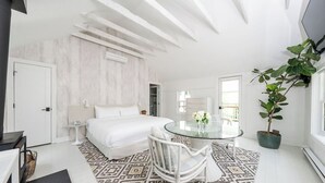 Quarto moderno com cama, mesa de cabeceira e mesa de vidro com cadeiras.