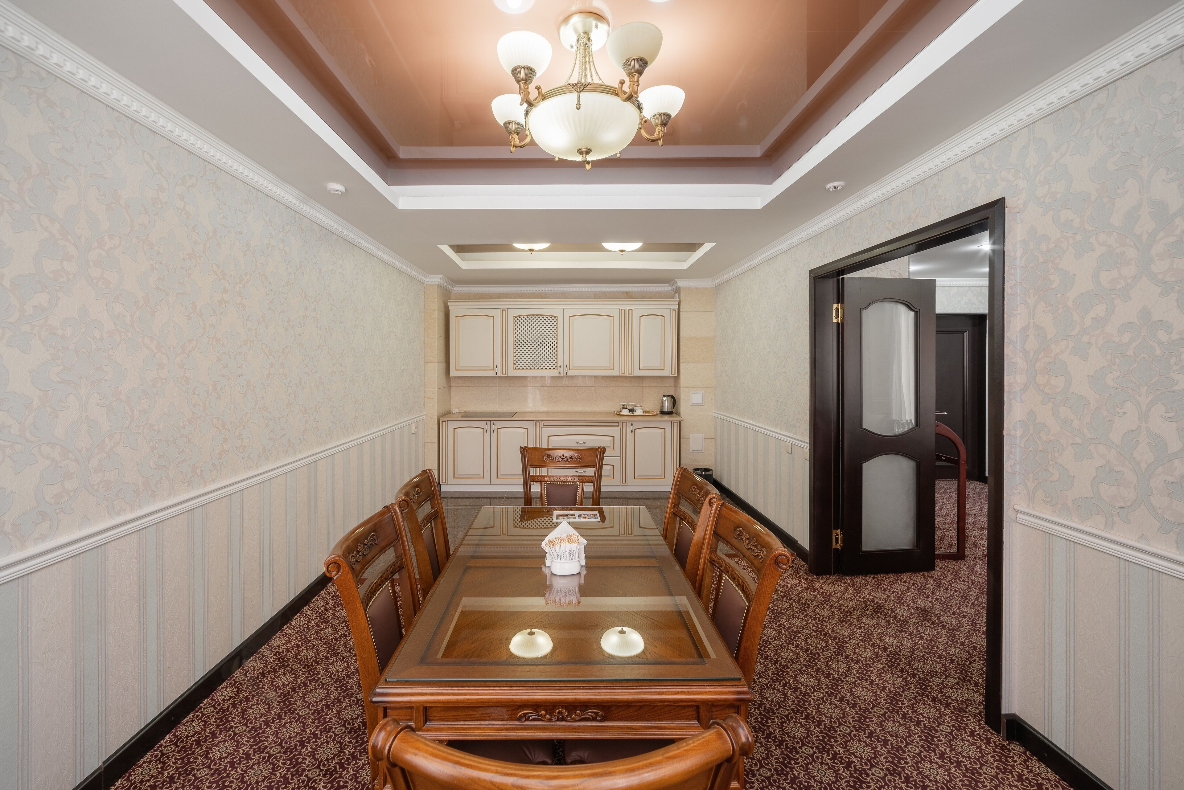 Uma sala de jantar formal com uma mesa comprida, cadeiras e um candelabro.