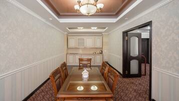 Uma sala de jantar formal com uma mesa comprida, cadeiras e um candelabro.
