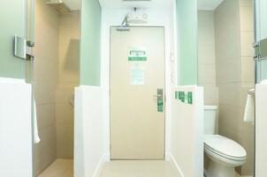 Casa de banho com chuveiro, sanita e porta com painel de comando.