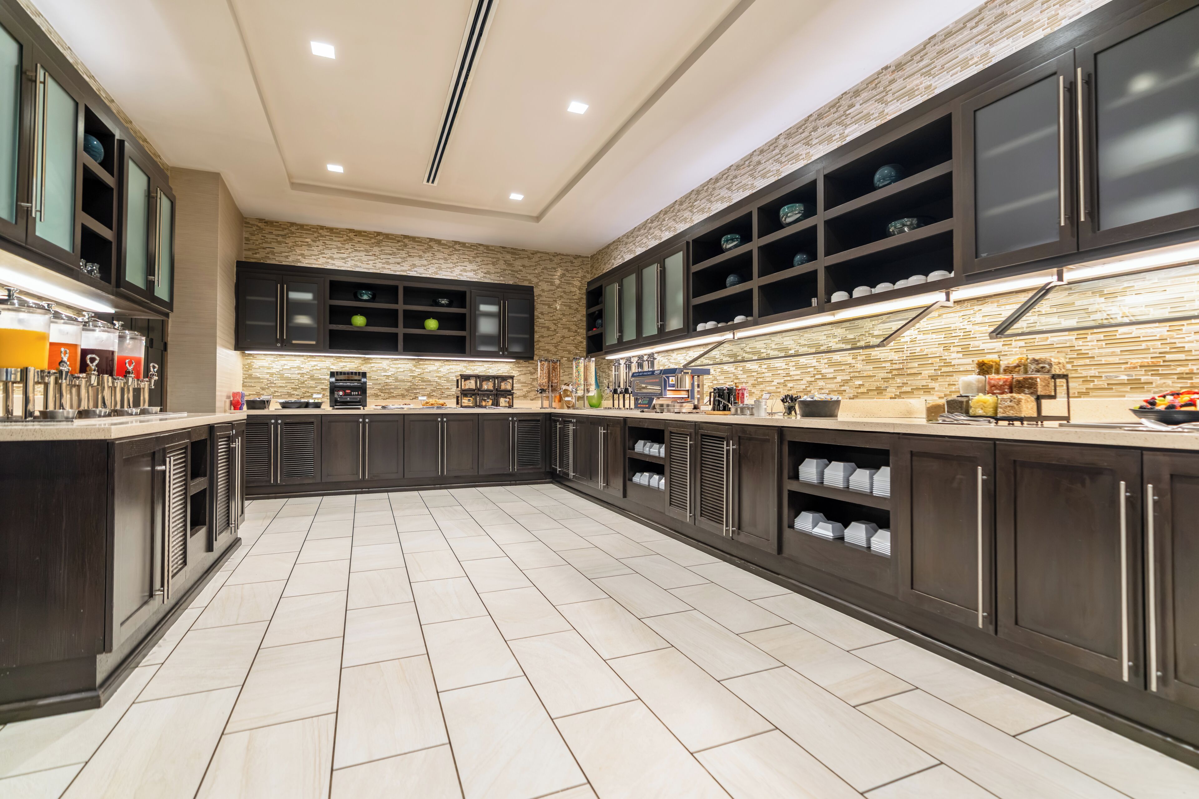 Cozinha moderna com armários escuros, piso ladrilhado e espaço para café embutido.