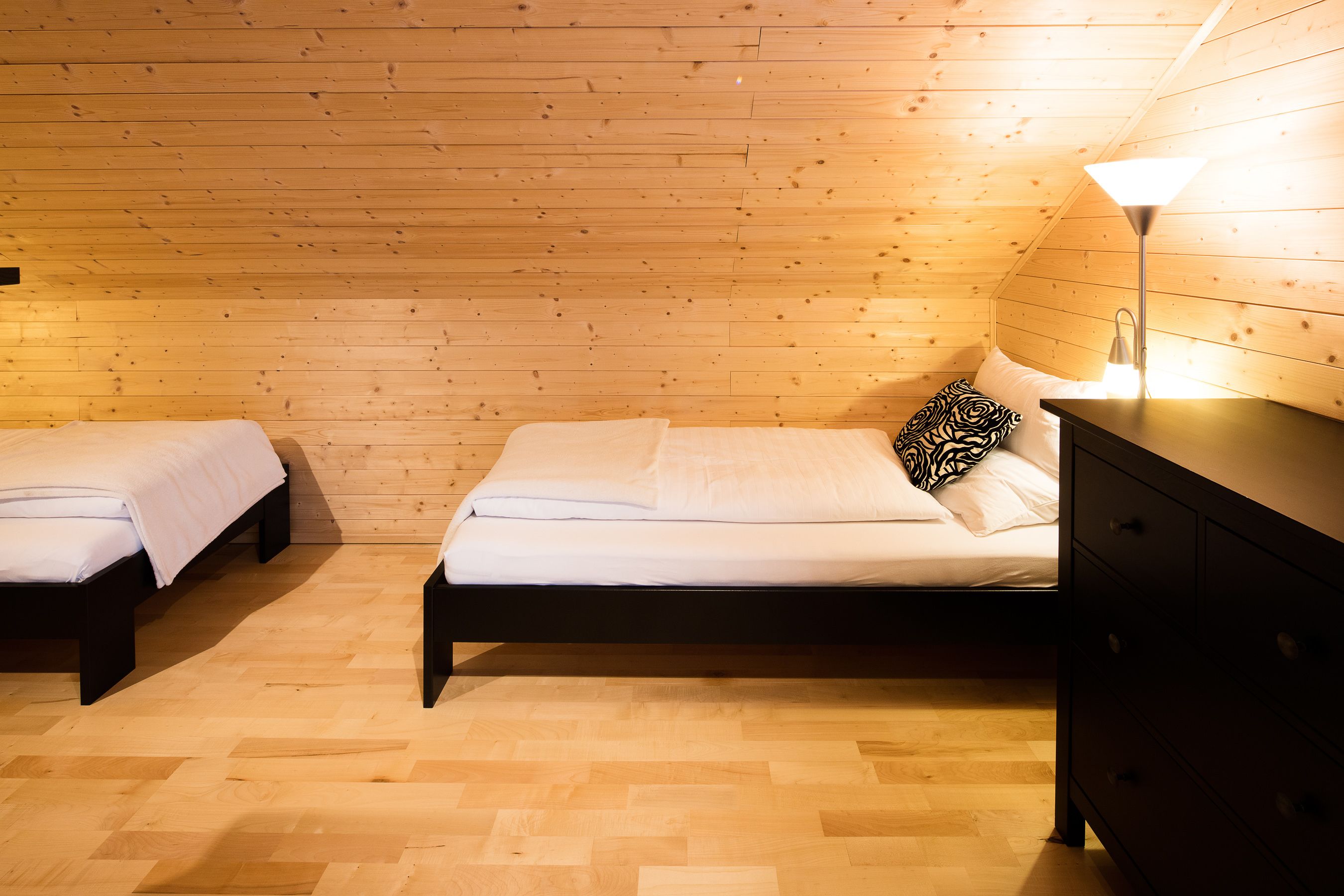 Quarto com duas camas, paredes de madeira e um aparador.