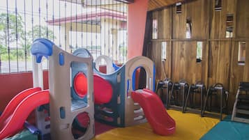 Uma área de recreação infantil com escorrega, estrutura de escalada e equipamentos de ginástica.