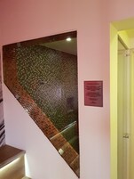 Uma escadaria com parede em mosaico e um aviso com instruções para hóspedes.