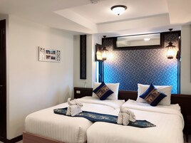Quarto de hotel com uma cama grande, duas luminárias fixadas na parede e papel de parede estampado.