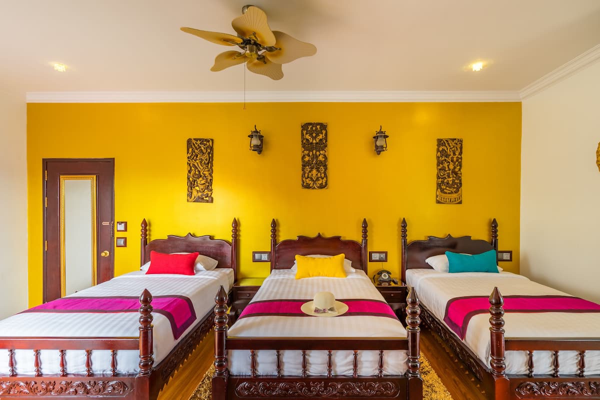 Quarto de hotel com duas camas, um ventilador de teto e arte decorativa nas paredes.
