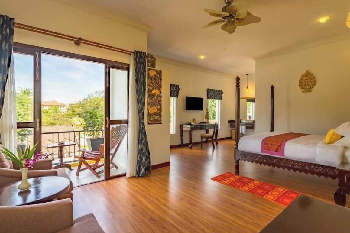 Quarto com cama, escrivaninha, cadeira, mesa e varanda com vista.