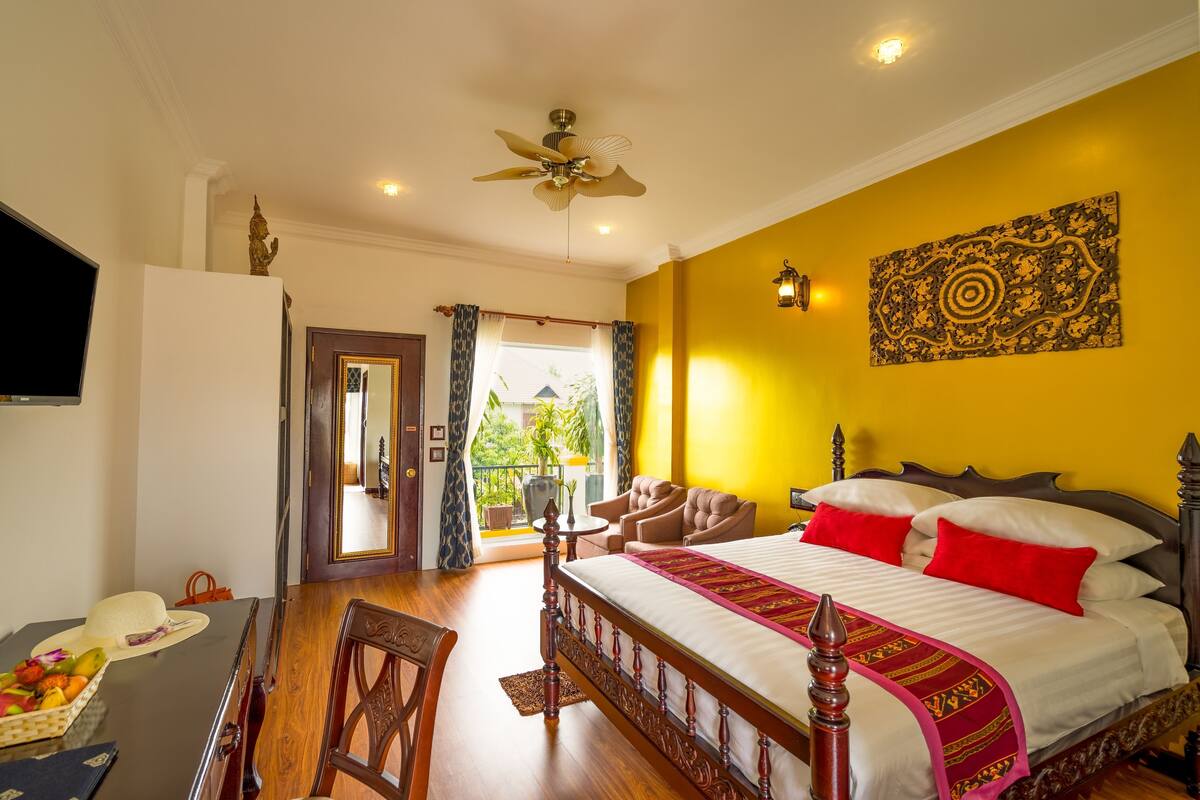 Quarto de hotel com cama, ventoinha no teto, mesa de jantar e vista para o exterior.