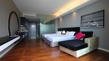 Quarto de hotel com duas camas, um sofá, uma escrivaninha com espelho e uma obra de arte na parede.