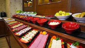 Buffet com diversos alimentos e uma planta em vaso na parede.