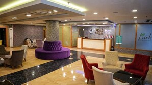 Um saguão de hotel com balcão de recepção, assentos confortáveis e piso reluzente.