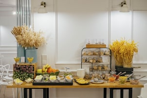 Uma mesa de buffet com diversos alimentos e acompanhamentos, incluindo frutas, saladas e bebidas.