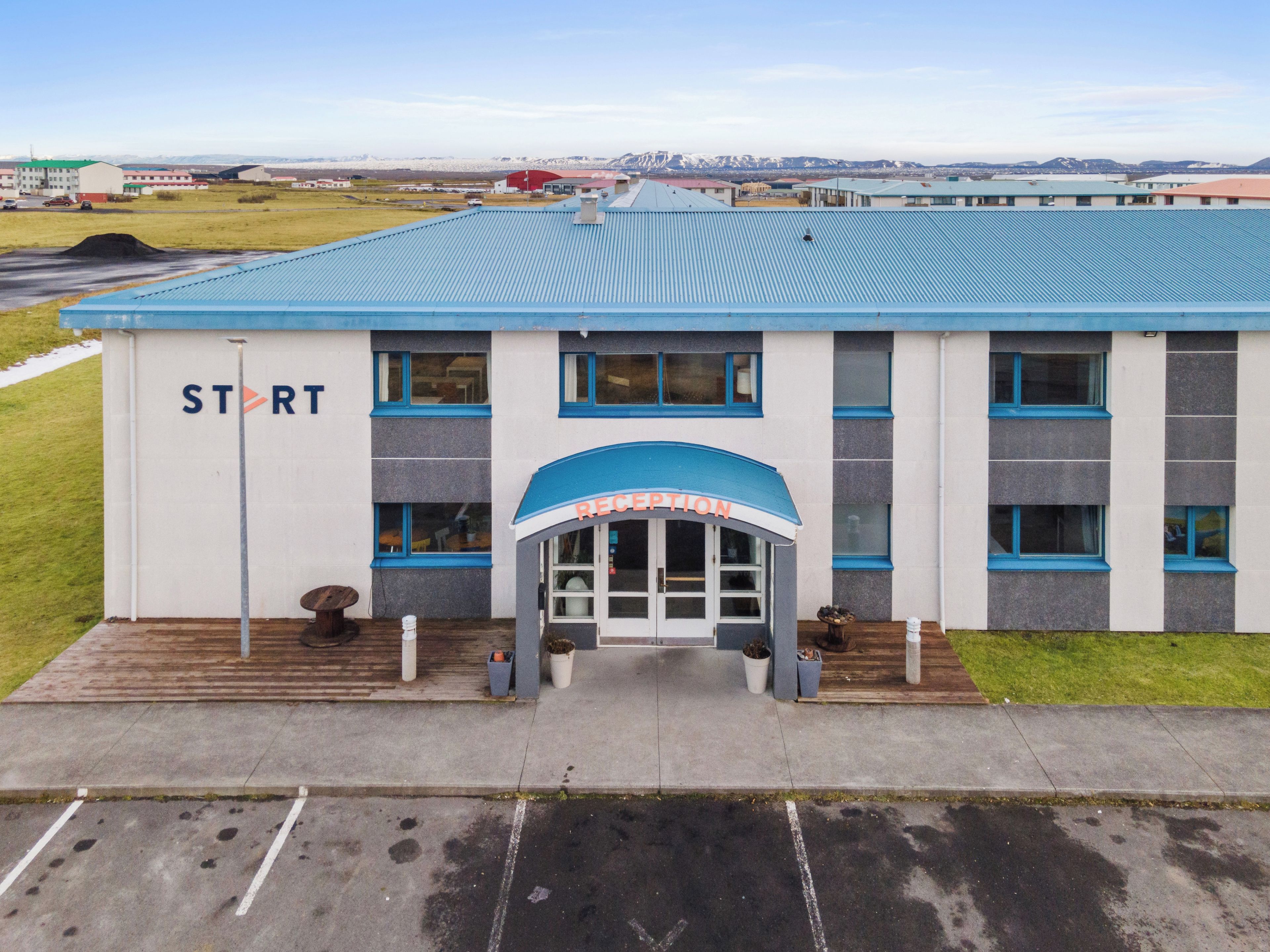 Um edifício com telhado azul e uma  área de recepção com uma placa.