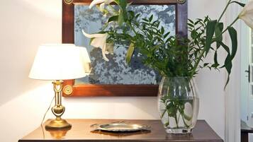 Uma mesa com uma lâmpada, um vaso com plantas e um espelho decorativo.