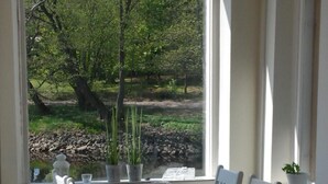 Uma área de refeições com uma grande janela com vista para uma área arborizada.