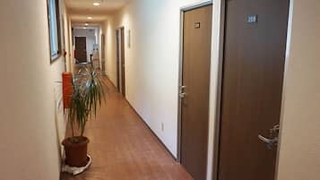 Corredor de hotel com planta em vaso, portas numeradas 210 e 208, e um dispensador de água.