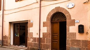 Um edifício com fachada de pedra, porta de madeira e janela com vista para a rua.