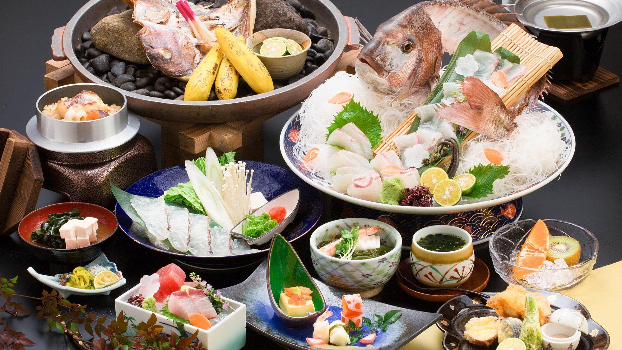 Diversos pratos da culinária japonesa, incluindo sashimi, sushi e tempura, dispostos sobre uma mesa.