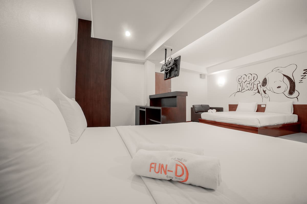 Quarto de hotel com uma cama, uma televisão na parede e um enfeite de parede.