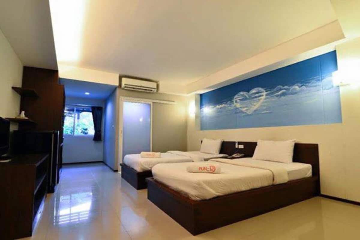 Quarto de hotel com duas camas, uma janela grande e um mural na parede.