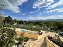 Área da piscina com vista para uma paisagem verde e montanhas ao longe.