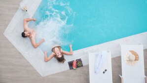 Vista aérea de uma piscina com duas pessoas relaxando na borda.