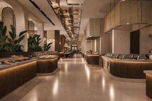 Um lobby moderno de hotel com uma recepção central, áreas de estar e um longo corredor.
