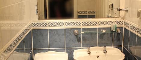 Casa de banho com sanita e lavatório, paredes em azulejo e espelho.