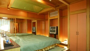 Um quarto tradicional em estilo japonês, com duas camas, uma televisão e uma pequena escrivaninha com abajur.