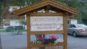 Uma placa de madeira com o texto "HONZNHOF APARTMENTHAUS HOLZNECHT" indicando um edifício residencial.