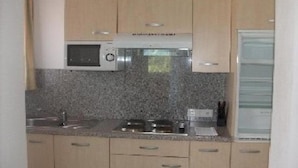 Uma cozinha com bancadas de granito, micro-ondas, forno embutido e armários de madeira.