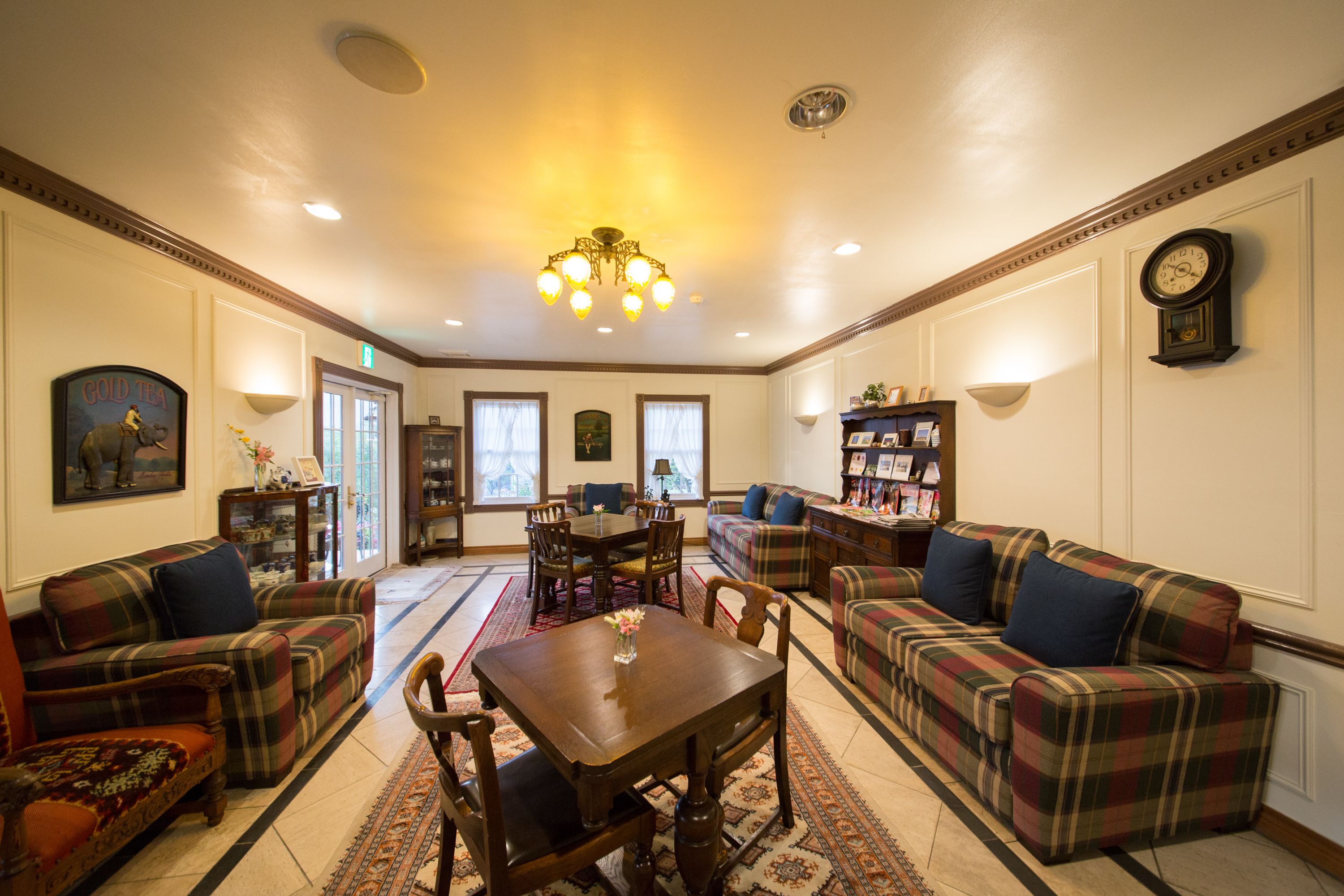 Uma sala de estar ampla com uma mesa de centro de madeira, sofás xadrez e um candelabro.