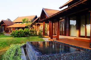 Um resort com várias cabanas de madeira, uma piscina e um jardim bem cuidado.