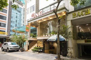 Hotel com fachada moderna, área de recepção visível e um carro estacionado na frente.