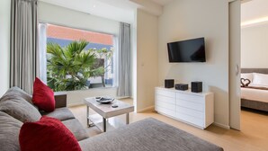Uma sala de estar moderna com sofá, mesa de centro, TV na parede e vista para o exterior.