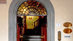 Uma entrada em arco com uma janela de vitrais, uma placa de latão e um sinal com um número.