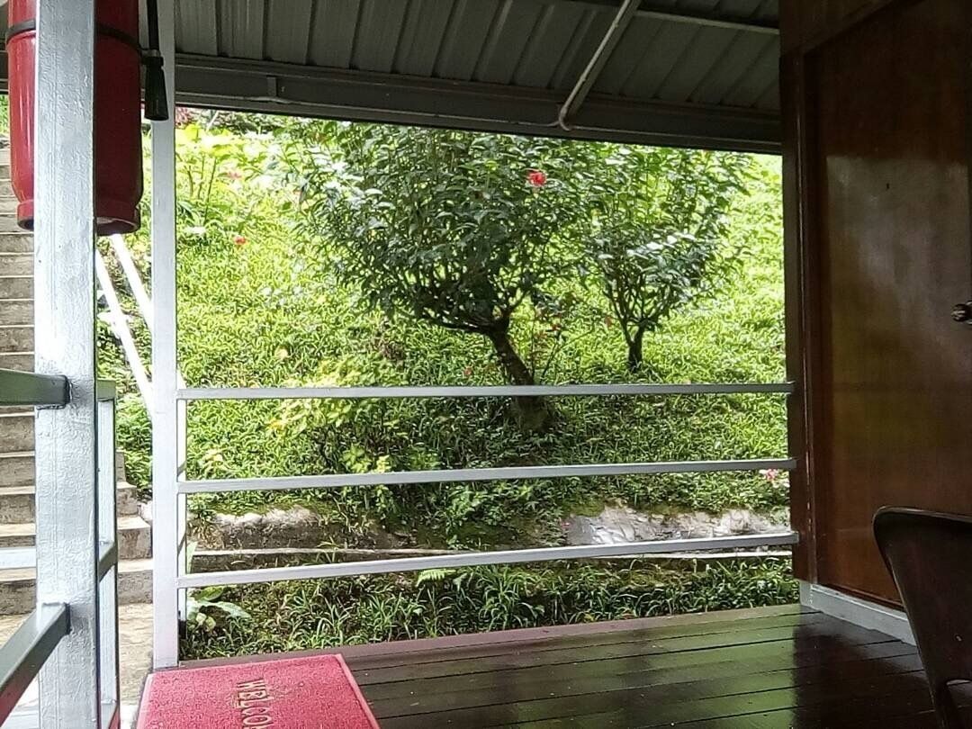 Uma área externa coberta com um banco de madeira, um tapete vermelho e um corrimão de metal.