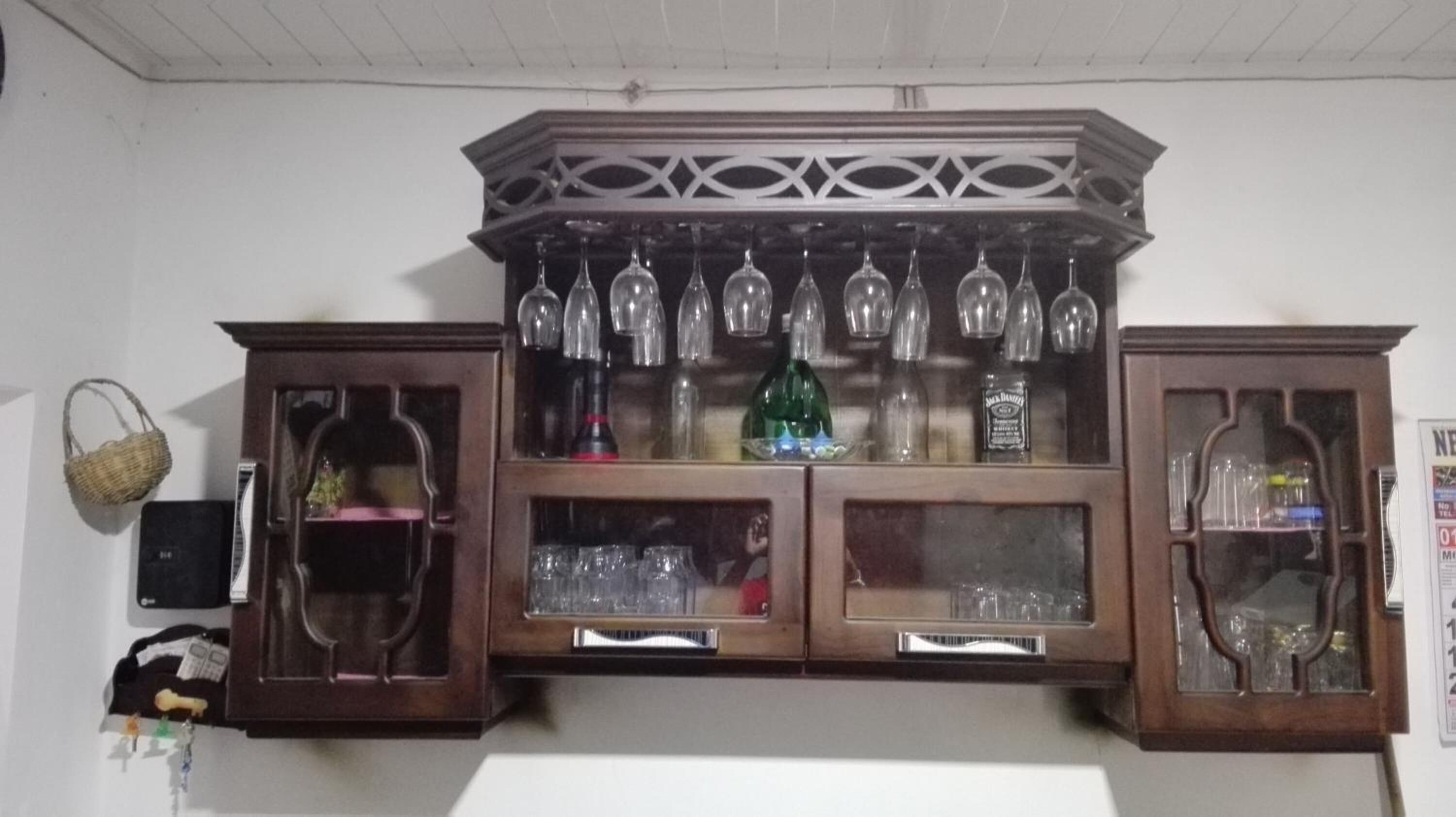 Um armário de madeira com portas de vidro que exibe diversos copos e garrafas.