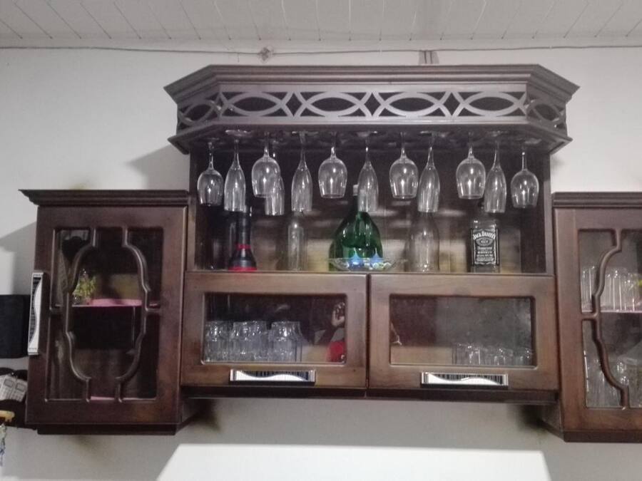 Um armário de madeira com portas de vidro que exibe diversos copos e garrafas.