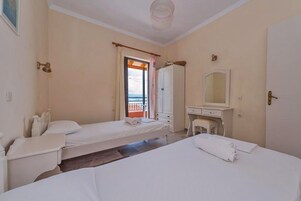 Quarto de hotel com duas camas de solteiro, uma penteadeira com espelho, uma secretária pequena e uma varanda com vista.