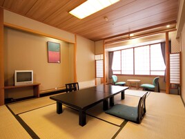 Quarto em estilo japonês tradicional, com tatames, uma mesa baixa e duas cadeiras.