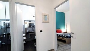 Quarto de hotel moderno com banheiro, cama e uma pequena área de estar.