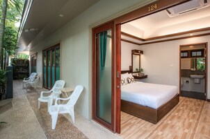 Quarto de hotel com cama, banheiro e área de estar com cadeiras.