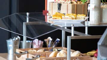 Disposição de buffet com diversos alimentos e uma planta ao fundo.