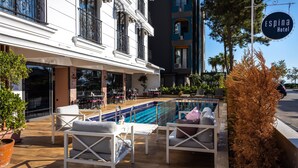 Um hotel com área externa para sentar, piscina e uma placa com a inscrição 