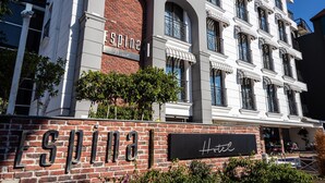 Um hotel com fachada de tijolos, janelas em arco e uma placa com a inscrição 'ESPOINA Hotel'.