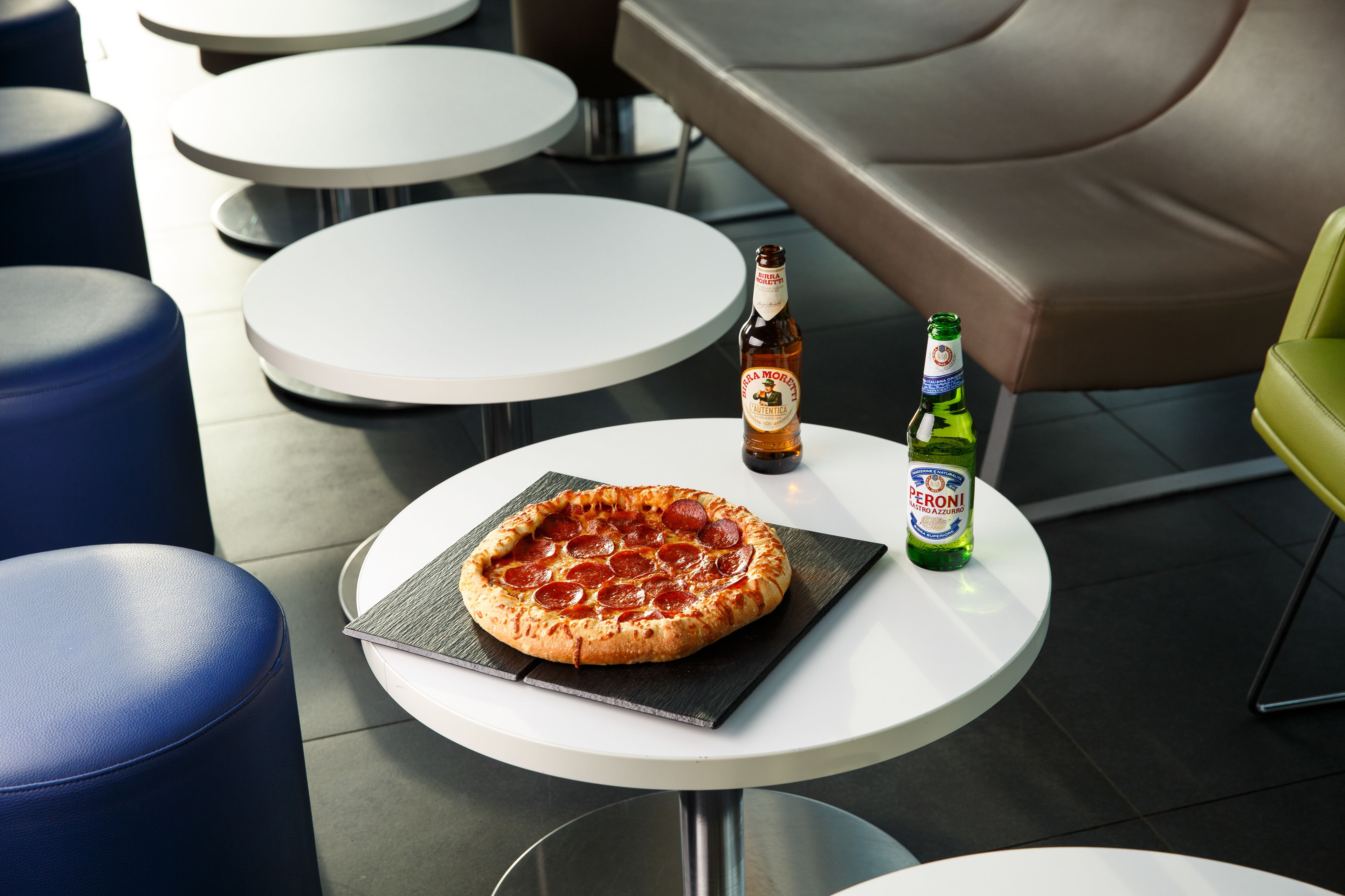 Pizza sobre uma mesa branca, com uma garrafa de cerveja e um apoio para copos.