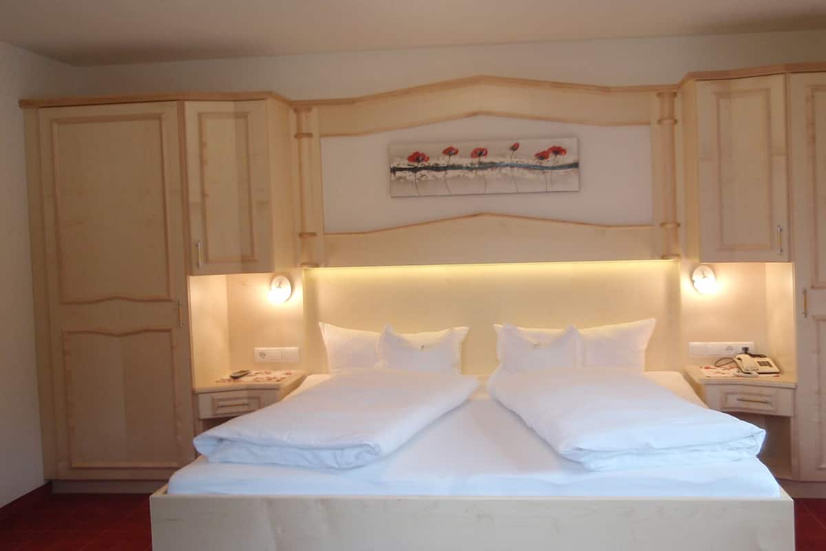 Quarto de hotel com uma cama grande, armários de madeira e um quadro na parede.